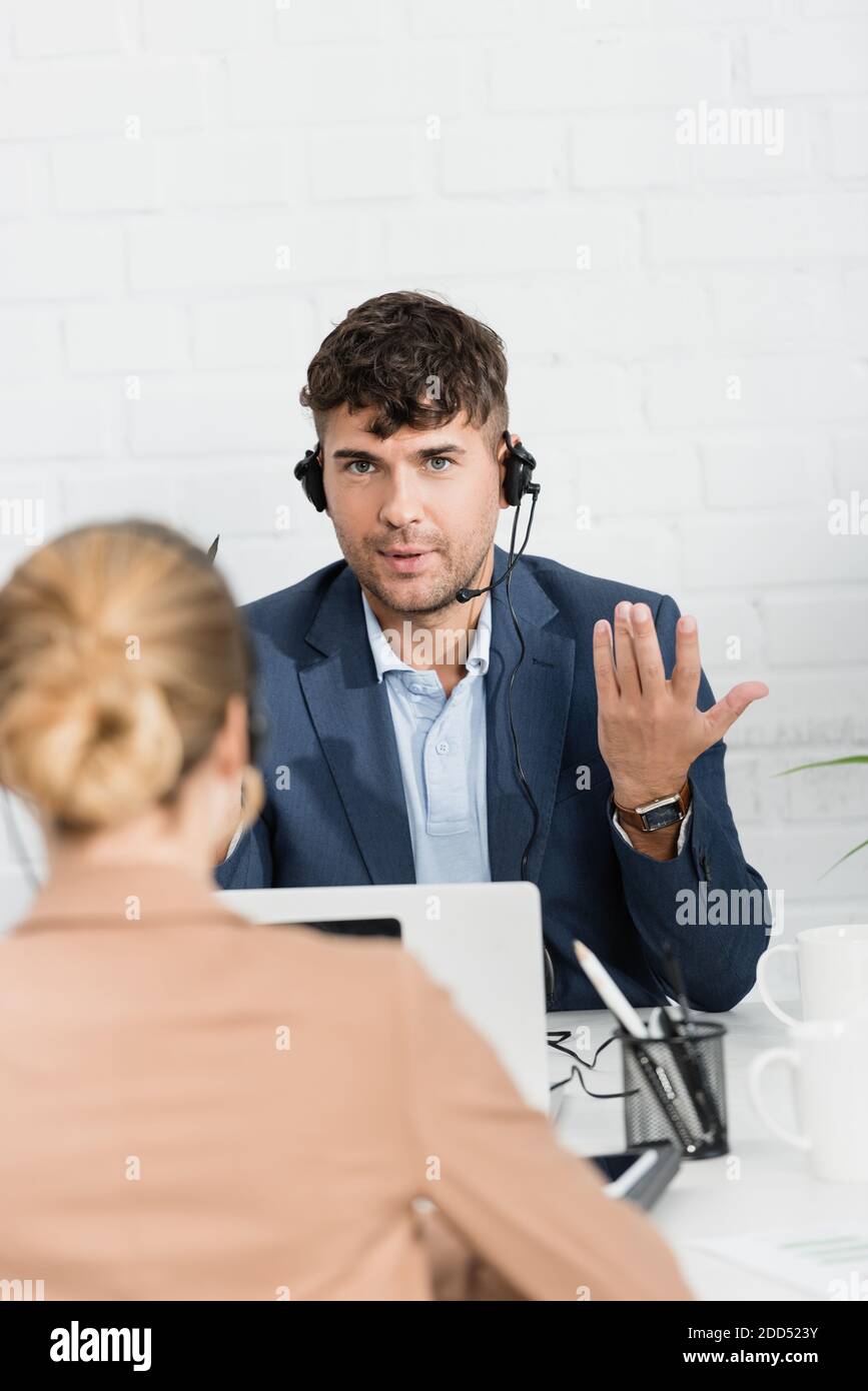 Back view of woman sitting near operator in headset gesturing at ...