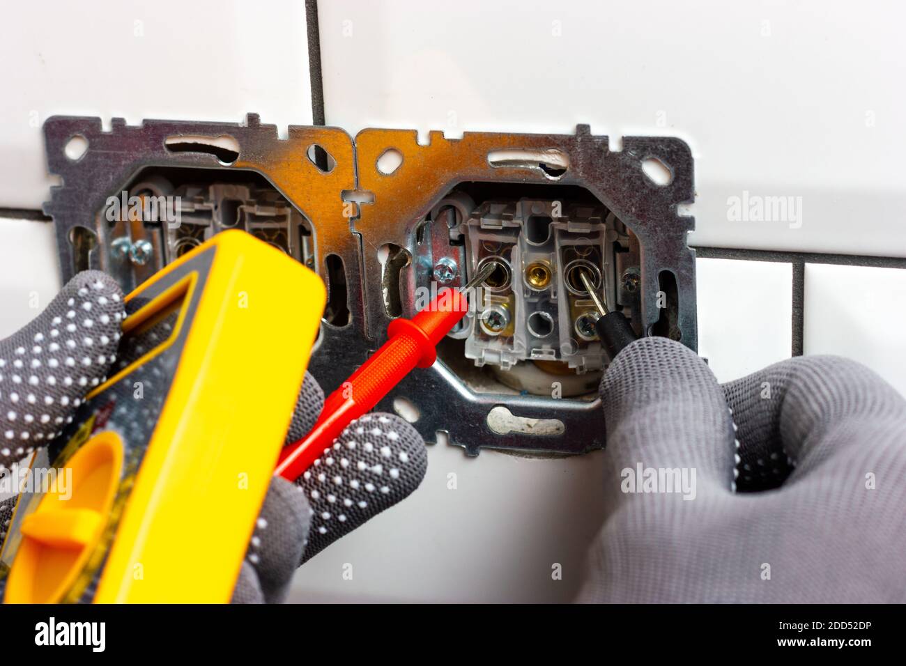 The guy checks the voltage in the disassembled electrical outlet with a ...