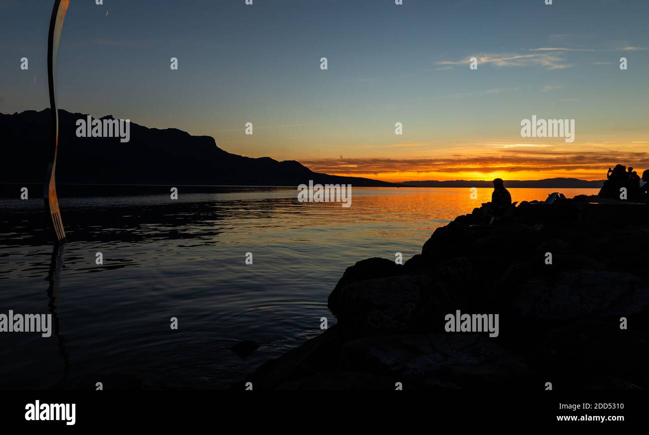 Modern sculpture - big fork in water of Geneva lake at beautiful sunset ...