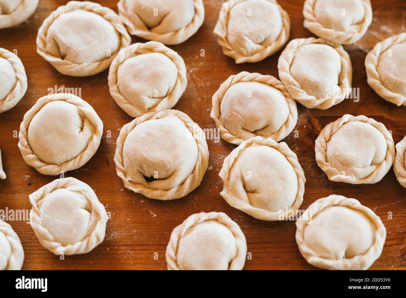 pile of small homemade uncooked dumplings with meat on kitchen table ...