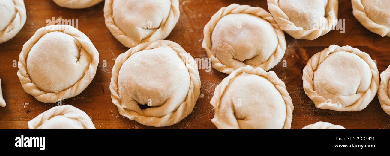 pile of small homemade uncooked dumplings with meat on kitchen table ...
