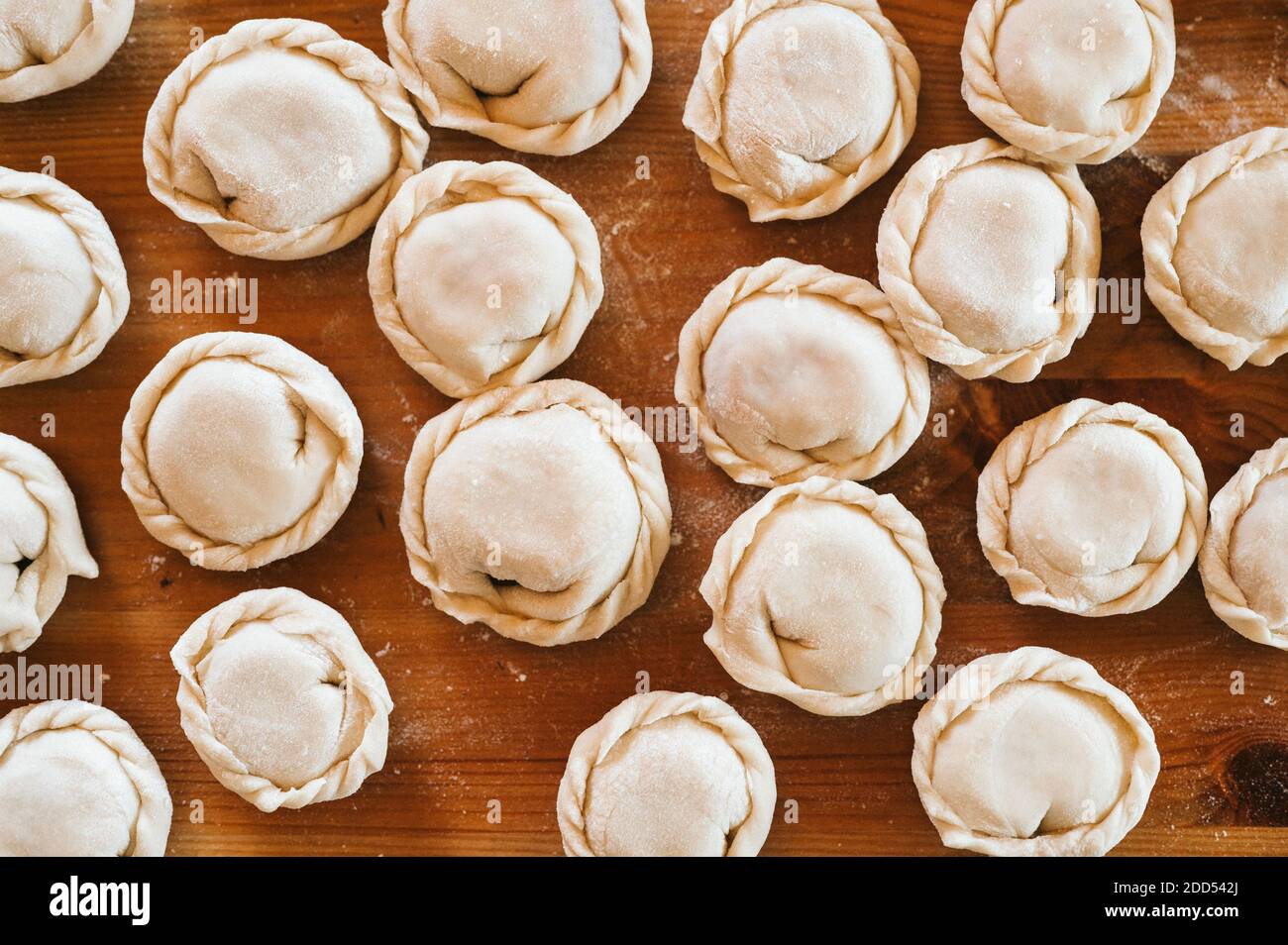 pile of small homemade uncooked dumplings with meat on kitchen table ...