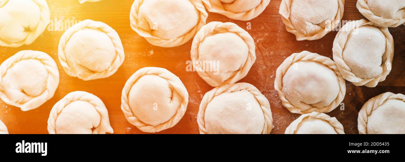 pile of small homemade uncooked dumplings with meat on kitchen table ...