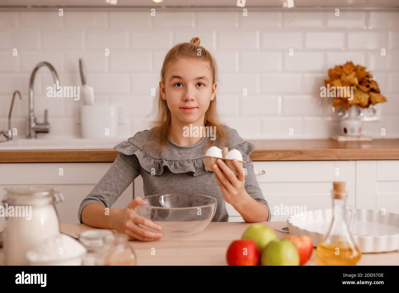Blonde teenage girl in a gray dress is going to cook traditional apple ...