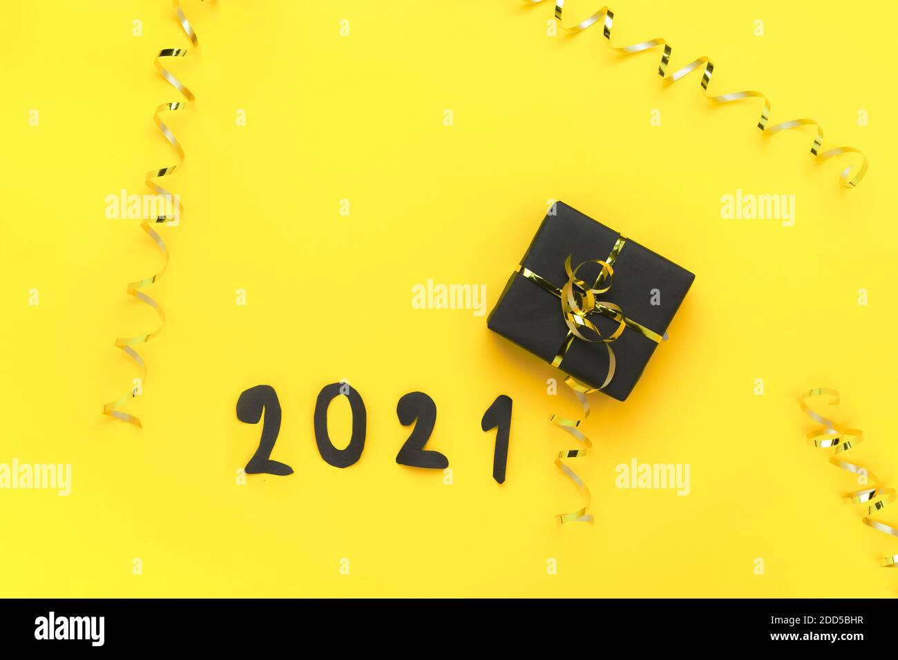 Christmas gift box wrapped in black paper and numbers 2021 on yellow ...