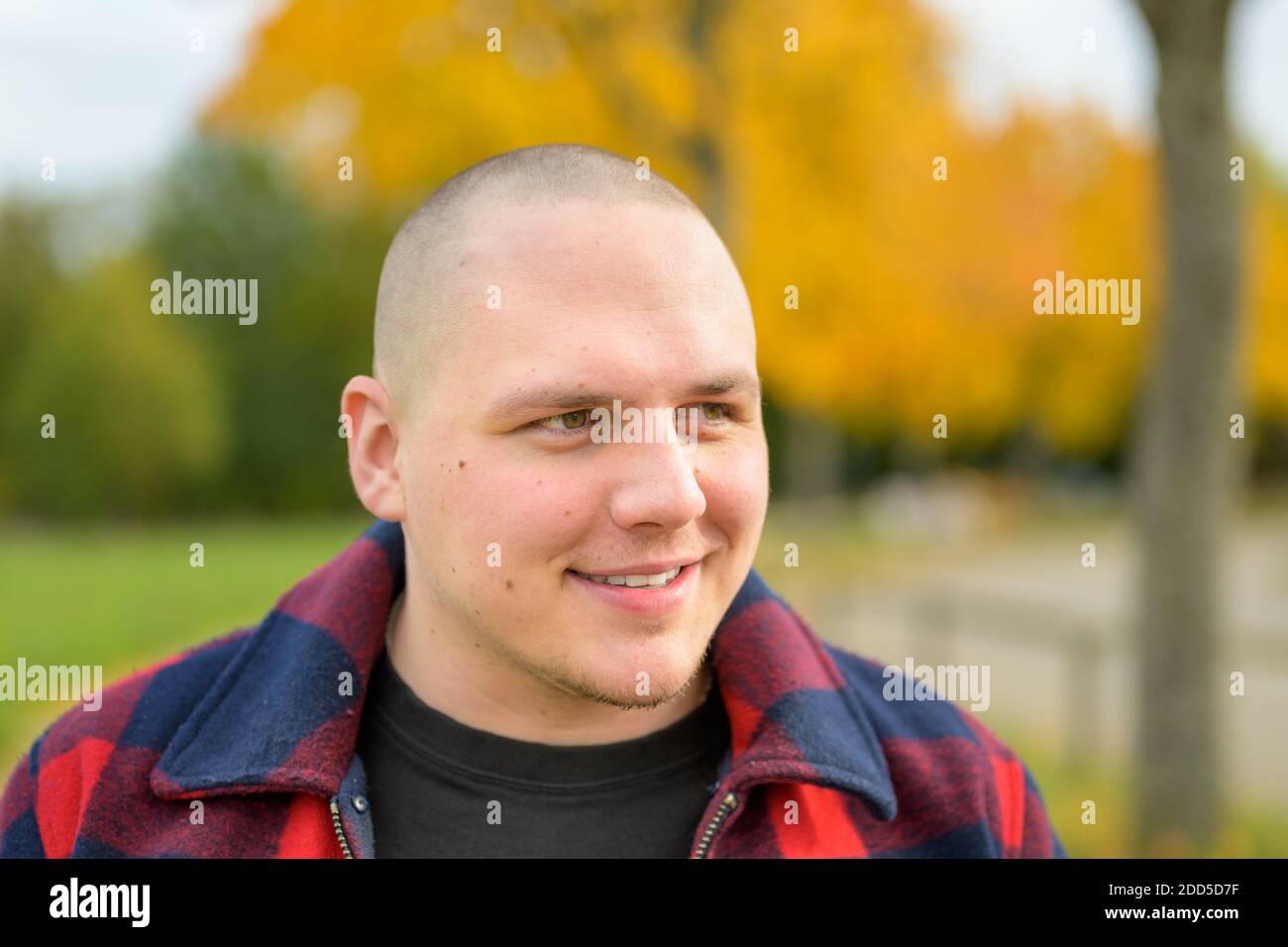 Young man smiling thoughtfully as he looks aside while standing ...