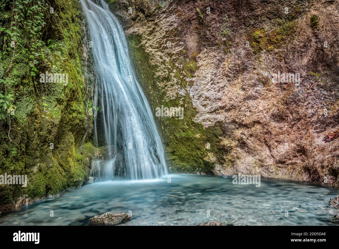Landscape view of a colorful waterfall and small basin at bottom ...