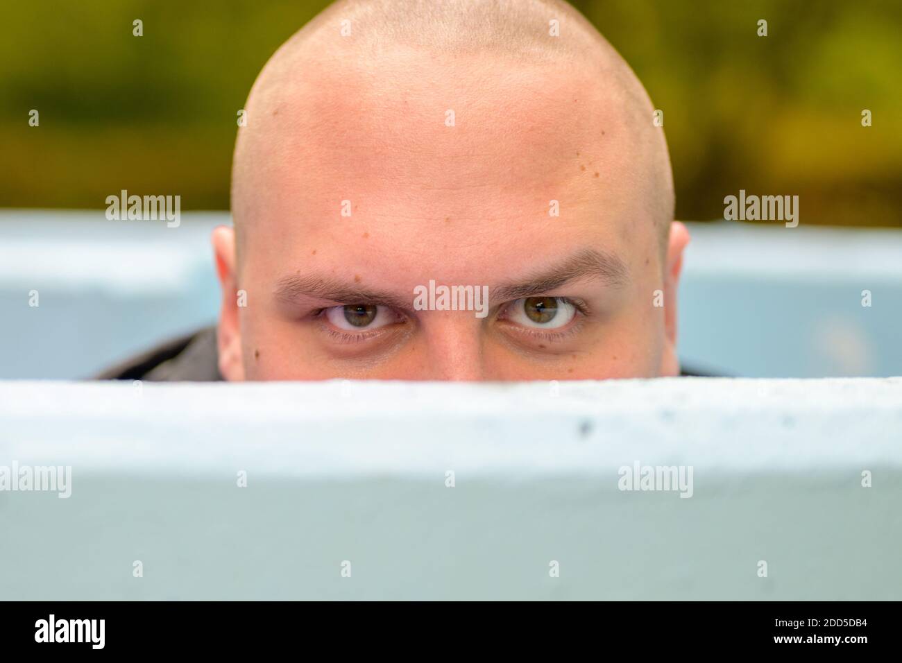 Close up of a young man with shaved head hunkering down in an outdoor ...