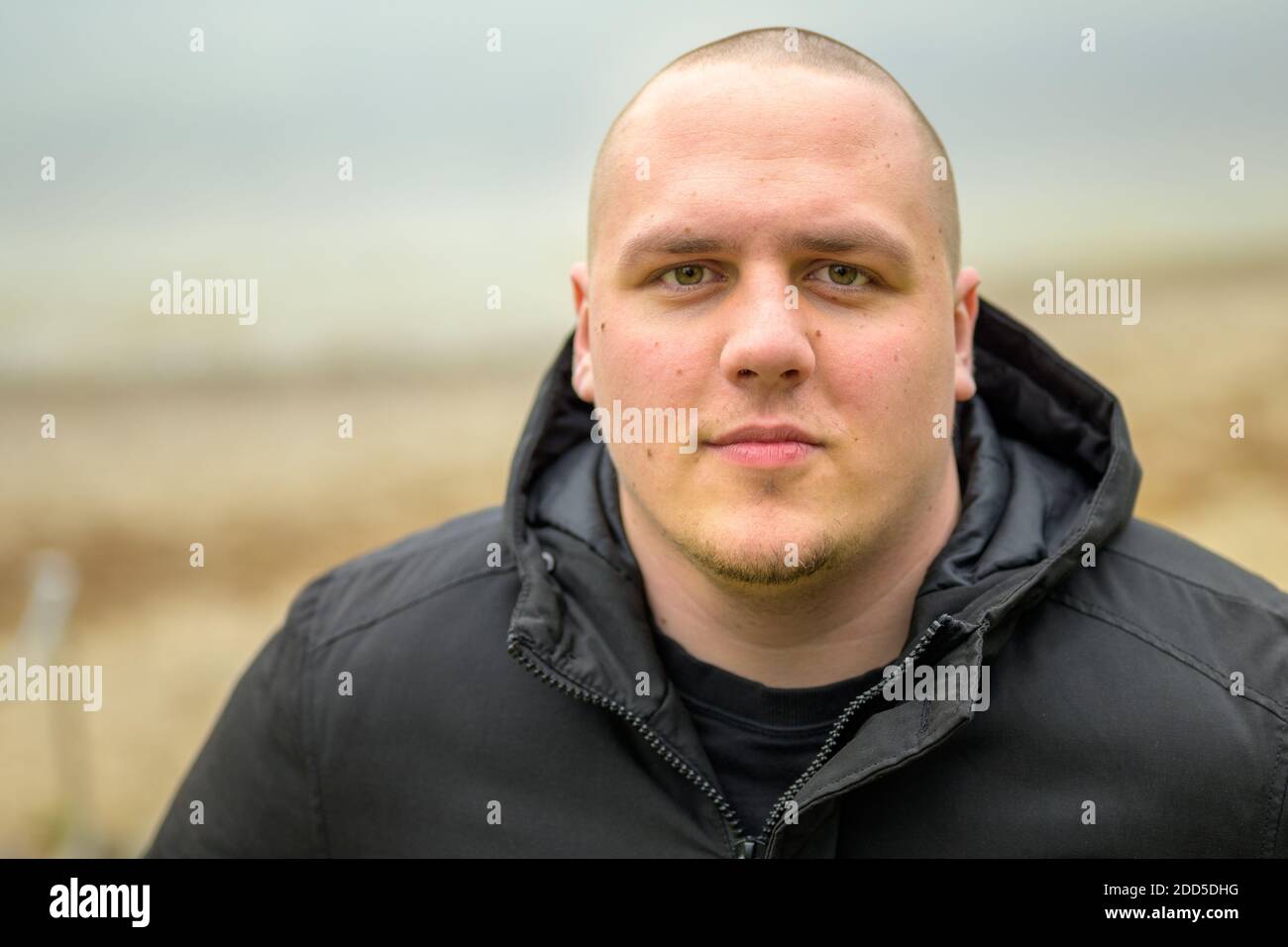 Serious young man staring at the camera with a pensive expression as he ...