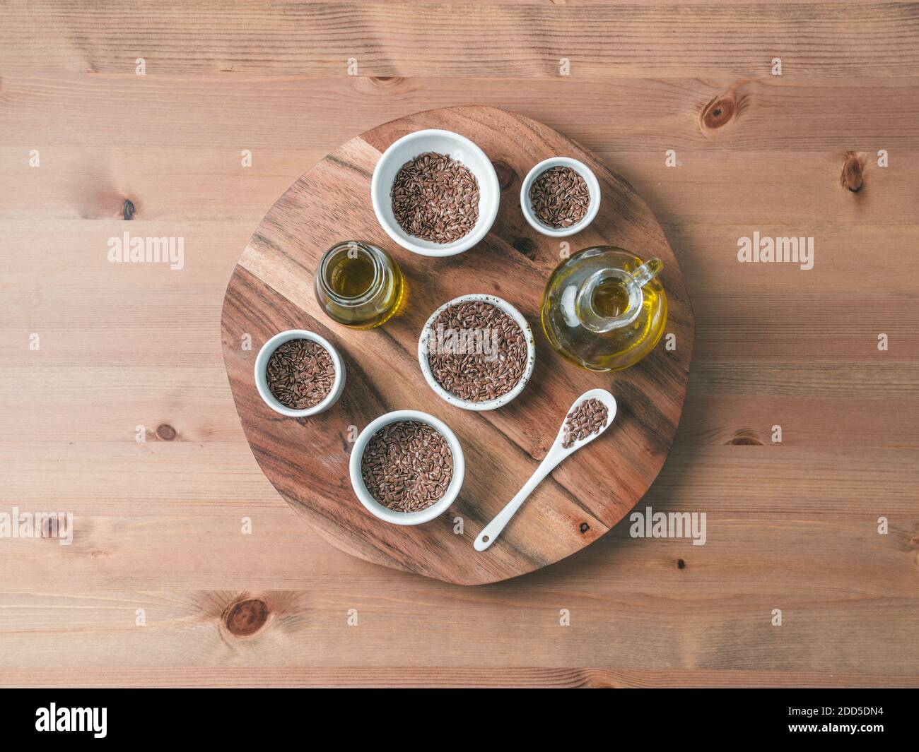 flax seeds and flaxseed oil on wooden table. Set of small bowls with organic flax seed or linen ...
