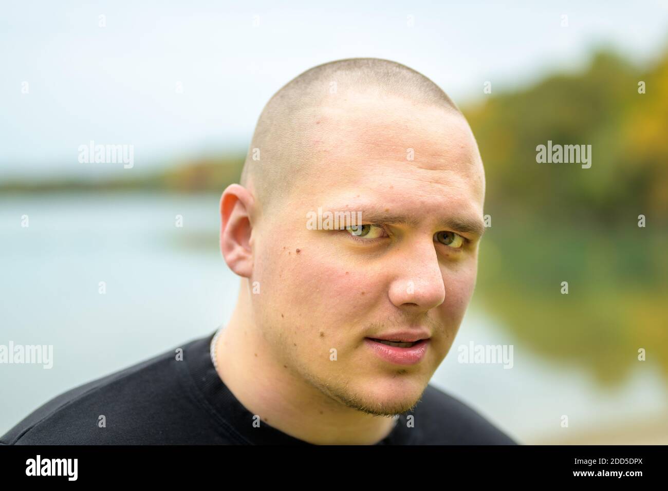 Unshaven young man in a close up head portrait looking to the side of ...