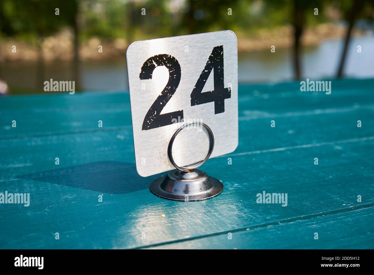 A metal restaurant, food order number, on a green picnic table. Number ...