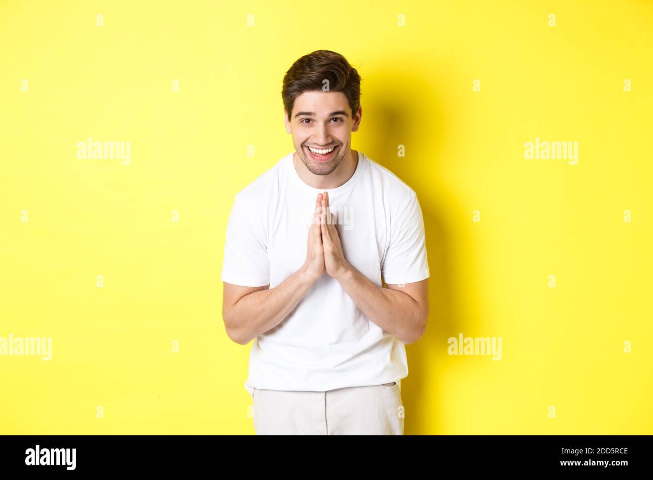 Handsome guy saying thank you, bowing and holding hands in namaste ...