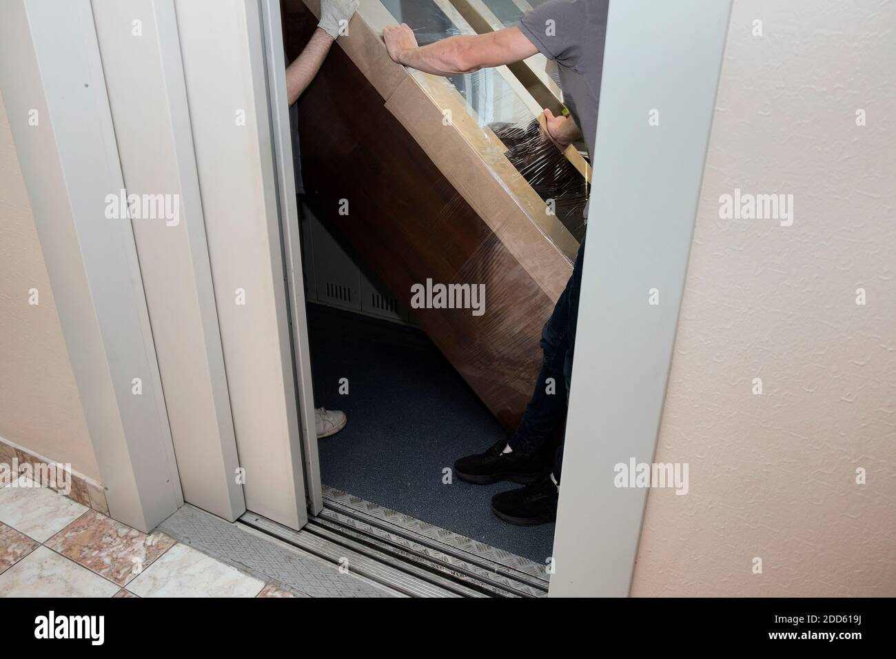 The workers loading furniture into a lift with open doors Stock Photo ...