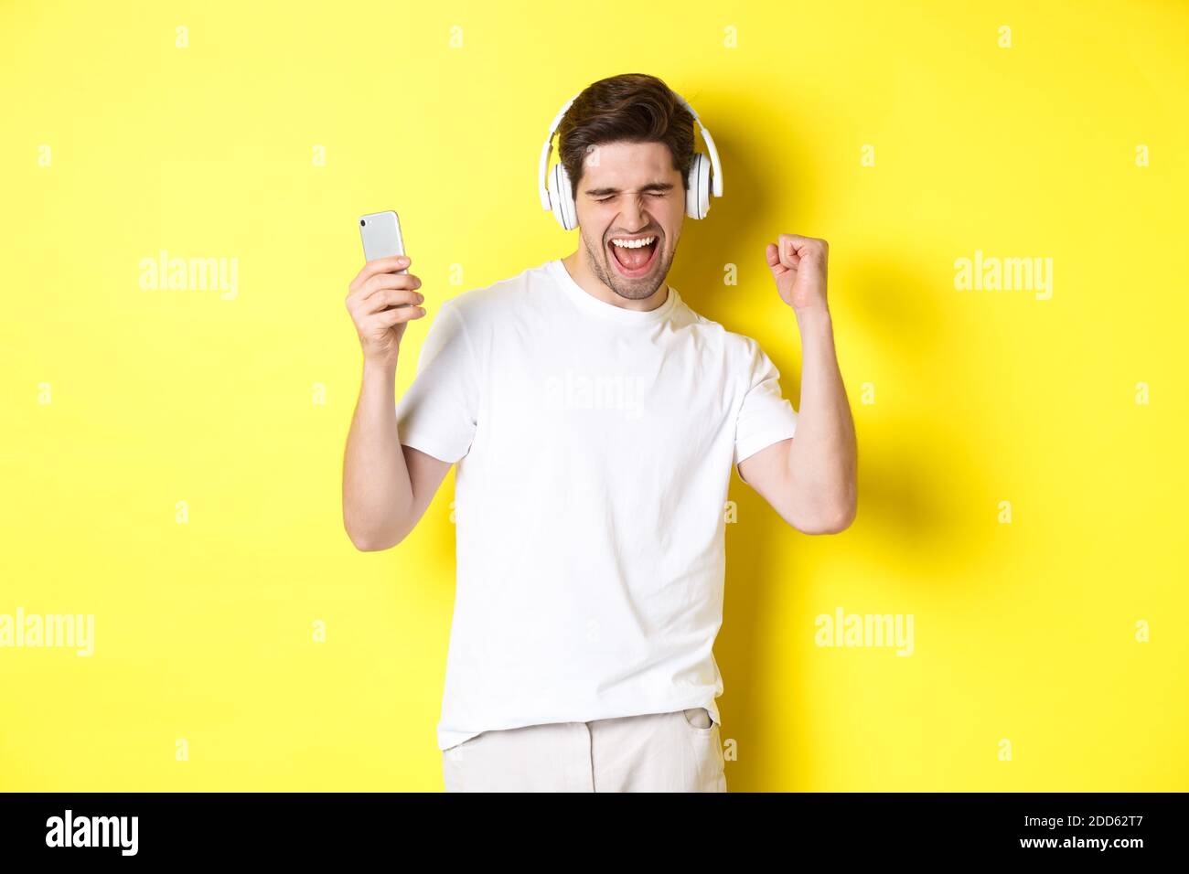 Happy man dancing and listening music in headphones, holding mobile ...