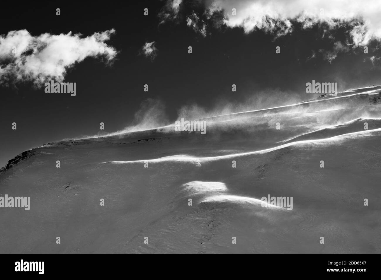 Off-piste slope during blizzard and sunlit sky with clouds in evening ...