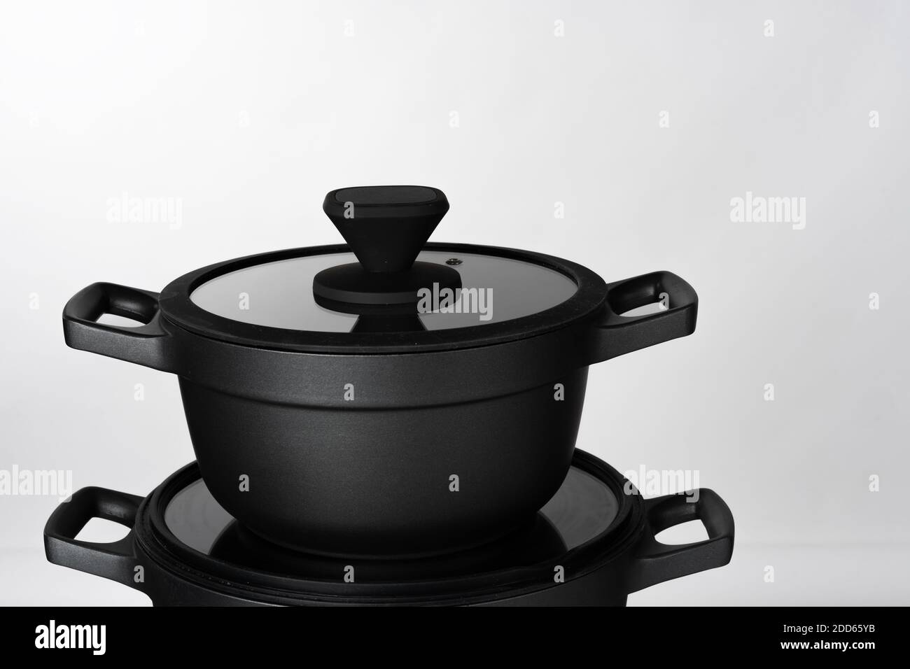 Black cooking pots on grey background front view Stock Photo - Alamy