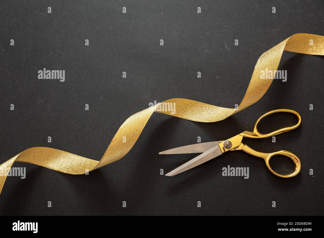 Grand opening. Gold scissors and golden silk ribbon, black background ...