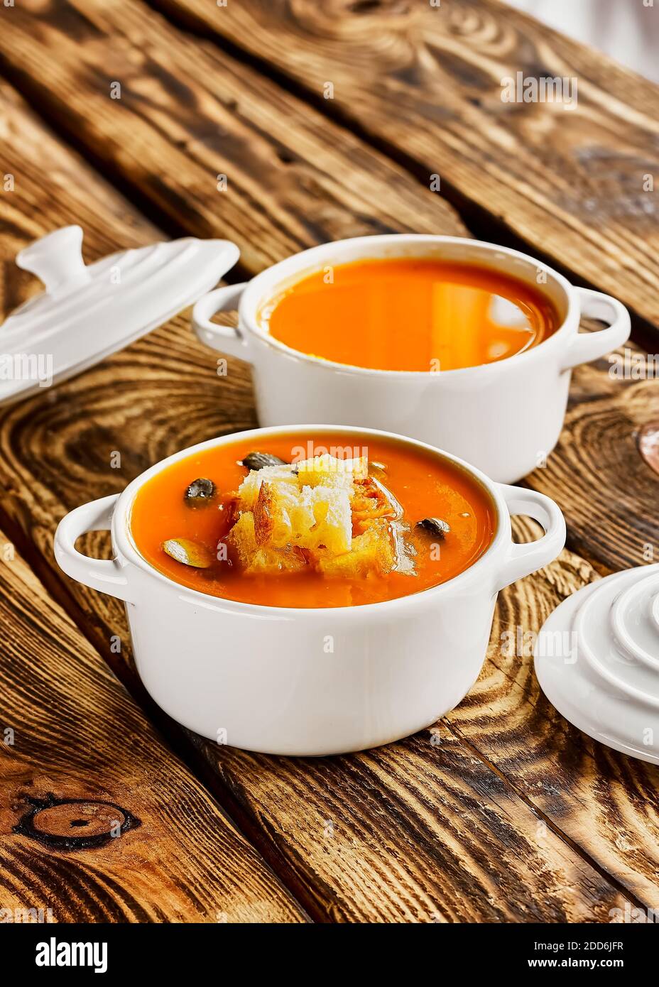 Vegetarian spicy autumn pumpkin cream soup served in white cocotte with ...