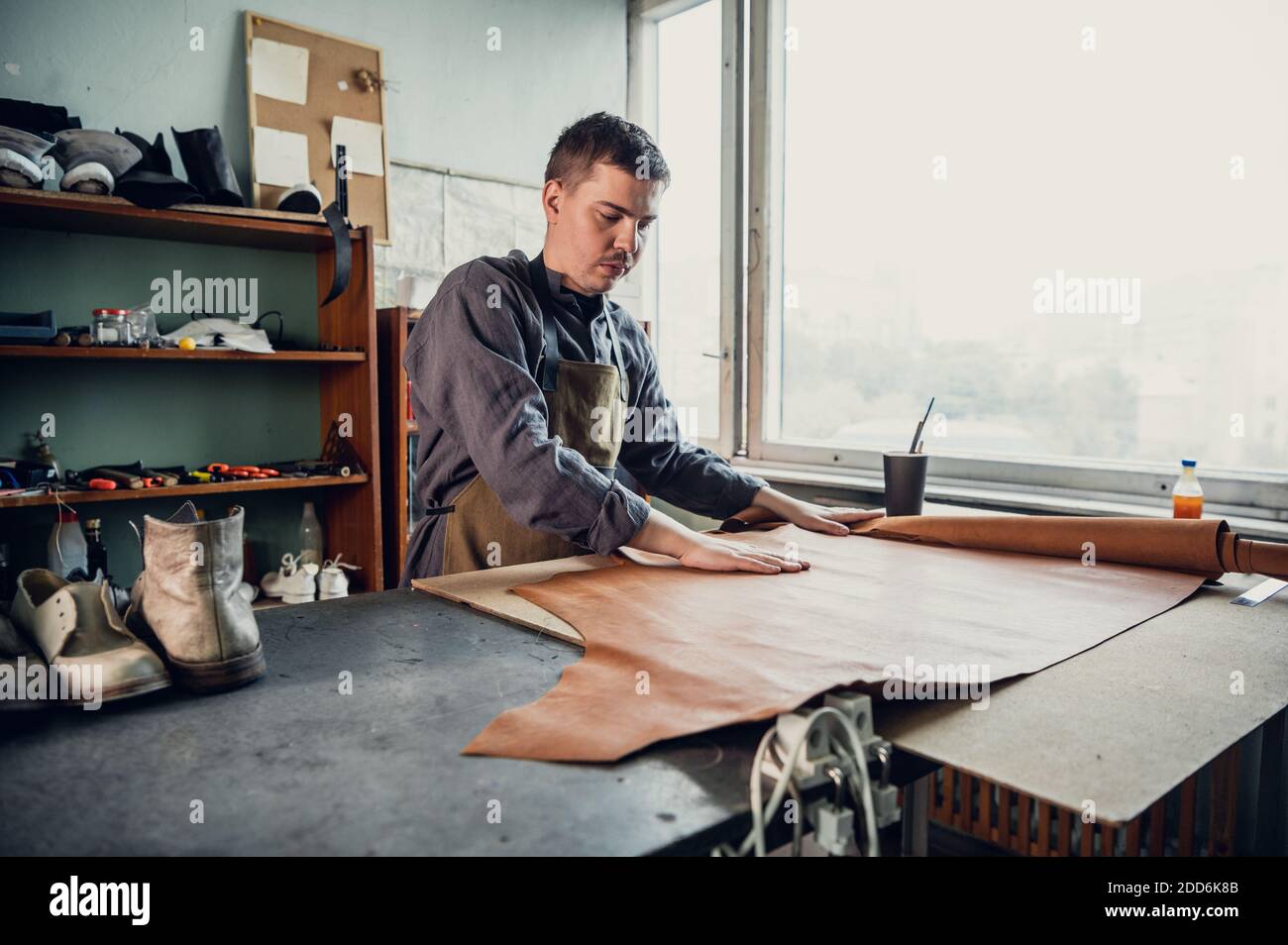 The initial stage of production of leather shoes, a young guy lays out ...