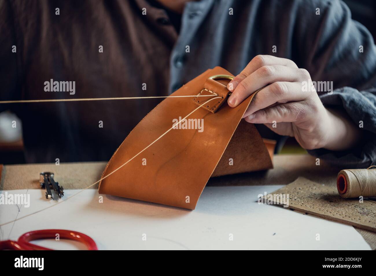 Close-up photo the hands of a skilled shoemaker make a bag from a piece ...