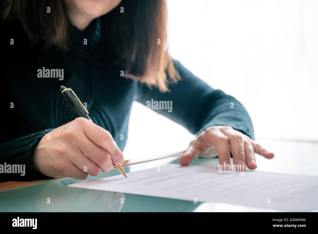 Woman in shirt signing document Stock Photo - Alamy
