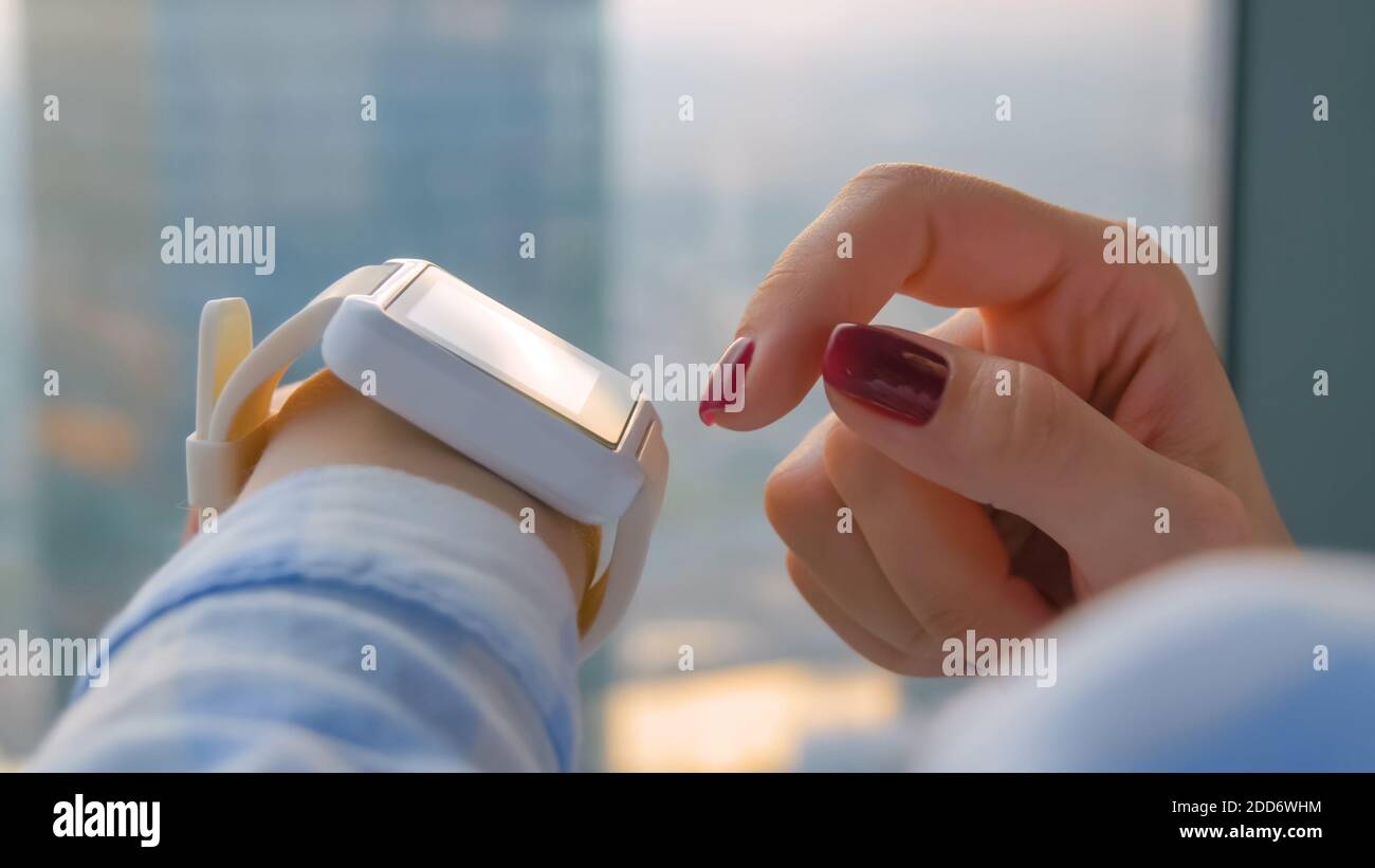 Woman hand using wearable white smart watch in office - close up side ...