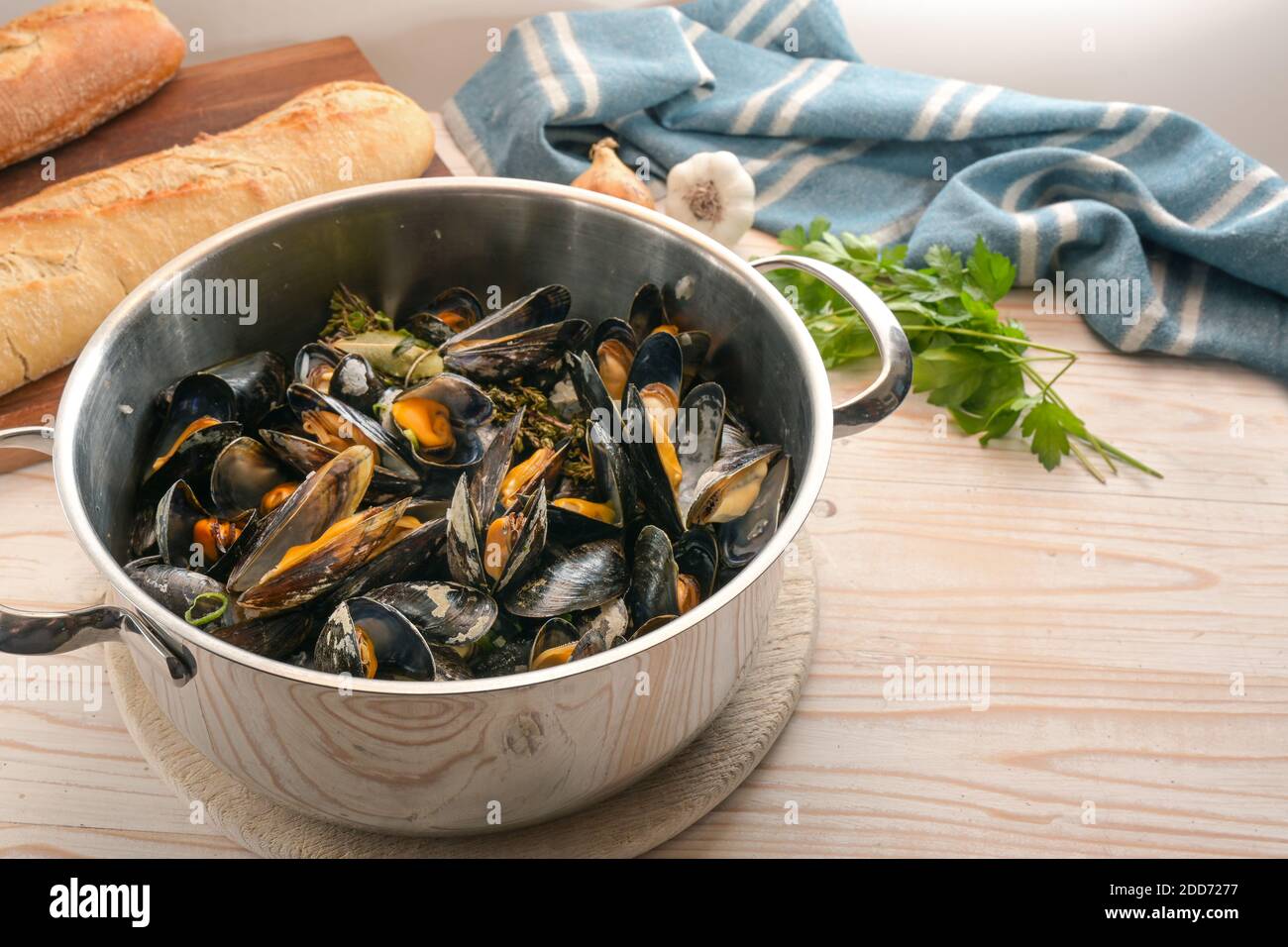 Freshly cooked mussels in a pot, bread, herbs and a blue towel on a ...