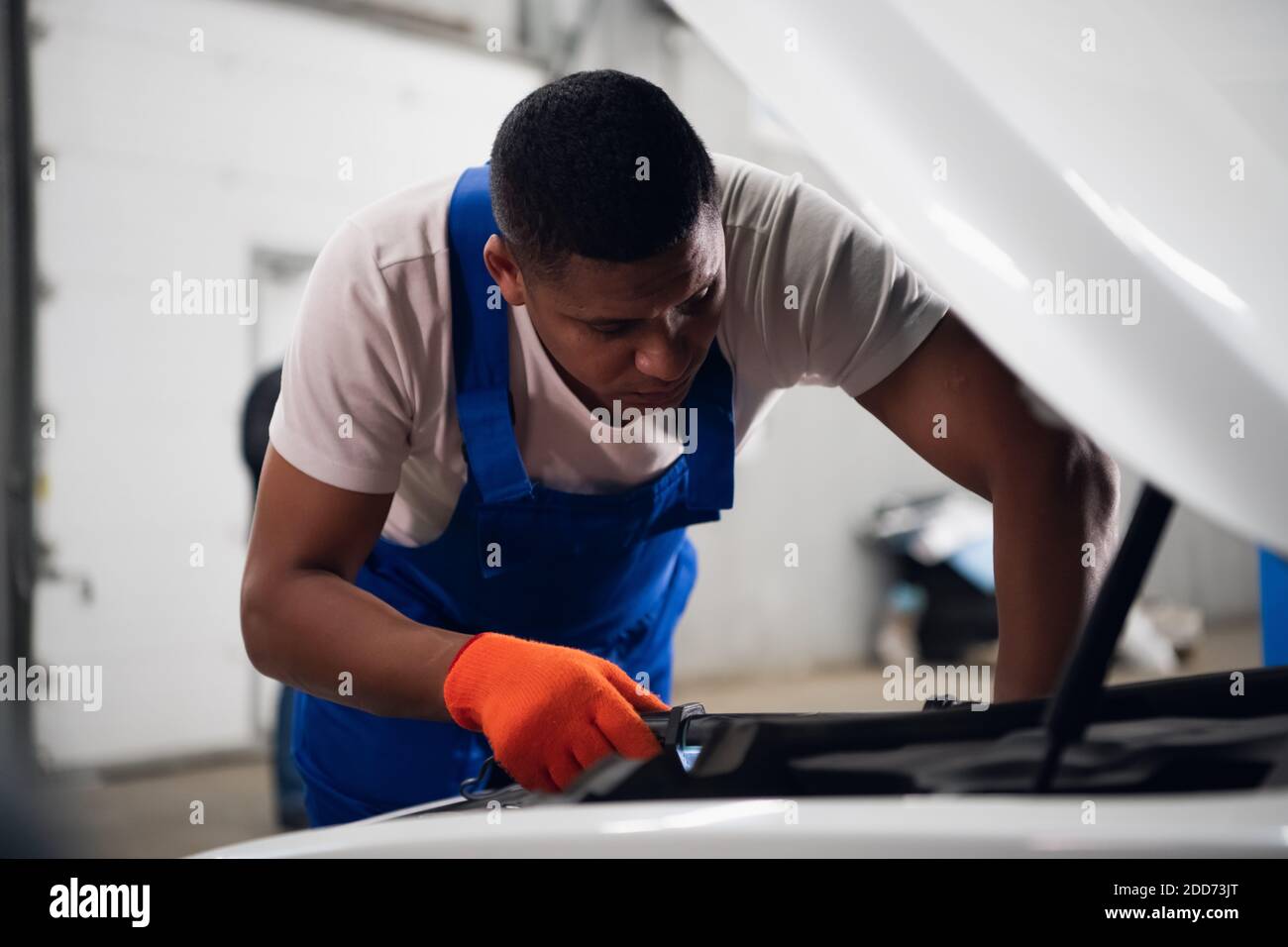 Uniform repairer uses a flashlight to inspect a automobile engine Stock ...