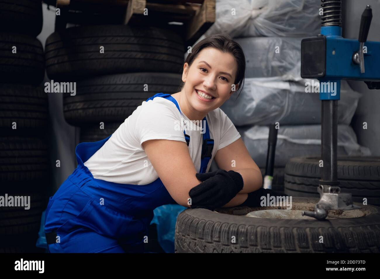 Woman in work clothes posing next to wheels and a machine tool and ...