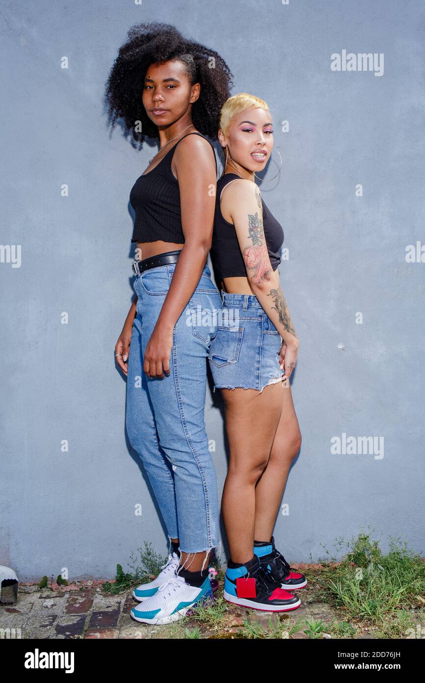 Two identically dressed young women stand back-to-back together Stock ...