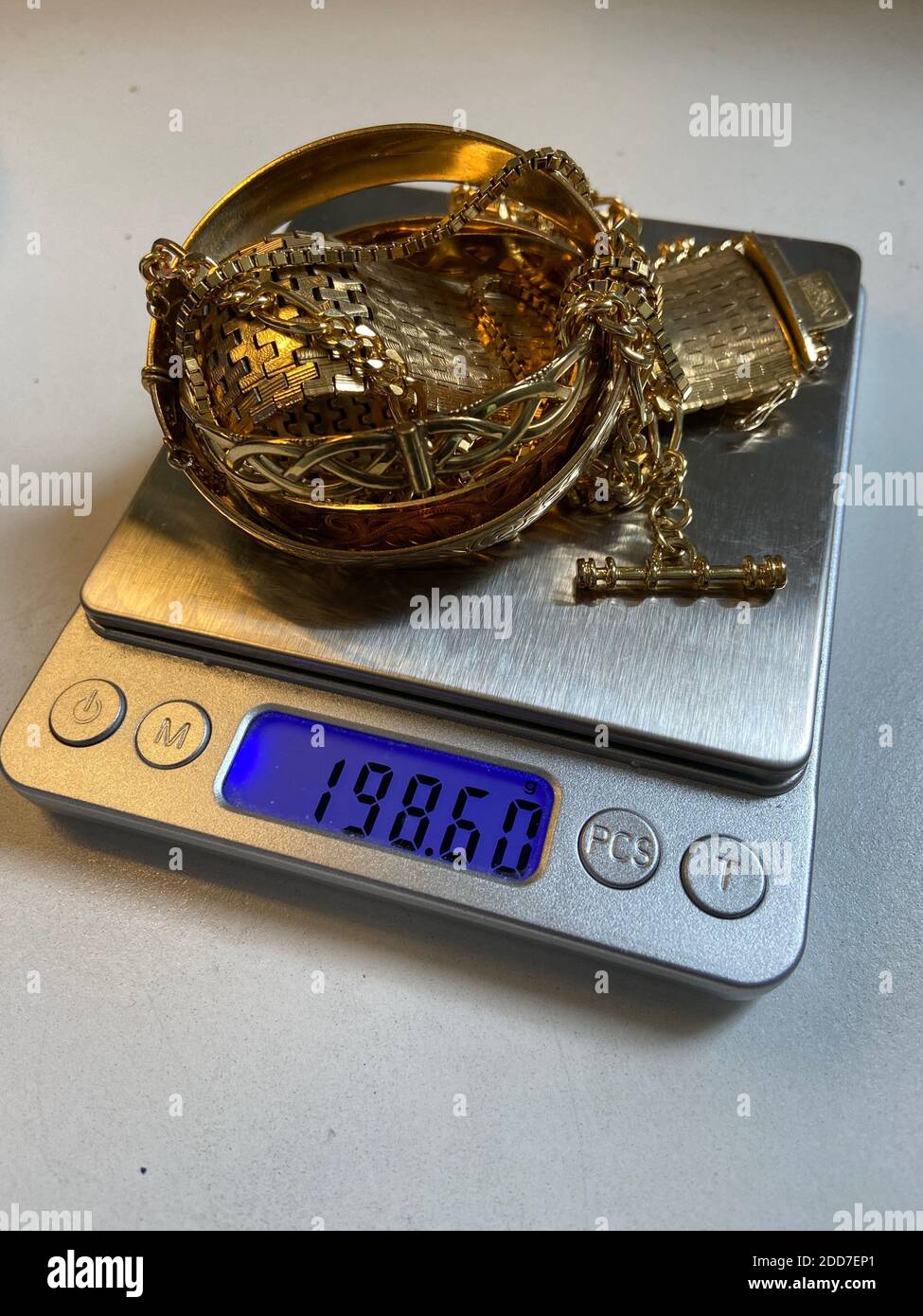 Gold scrap pile chains and bangle jewelry on scale being weighed at ...