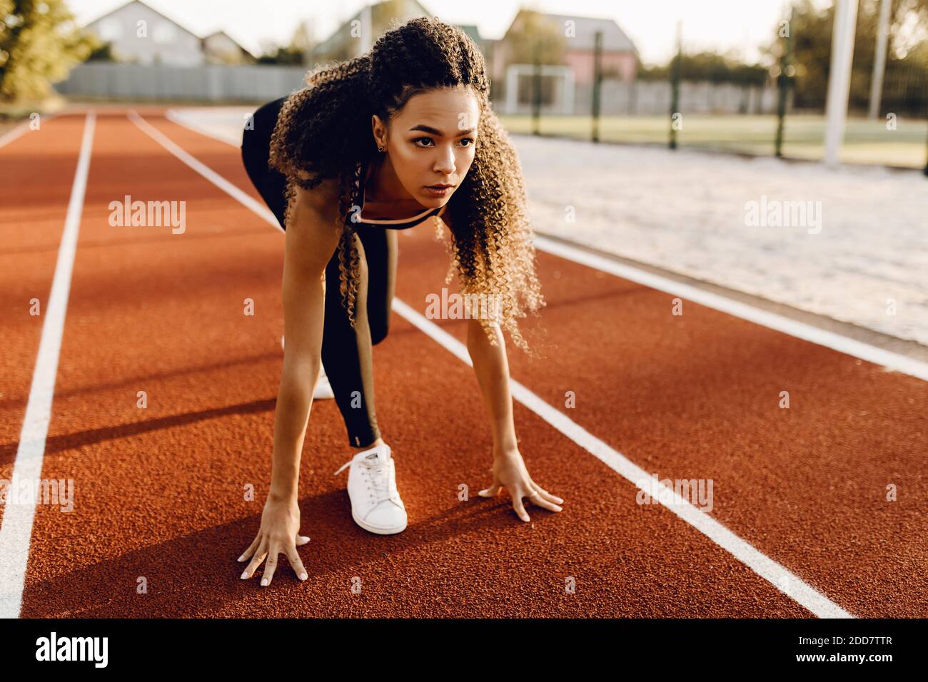 Young sportive woman runner at stadium starting line getting ready for ...