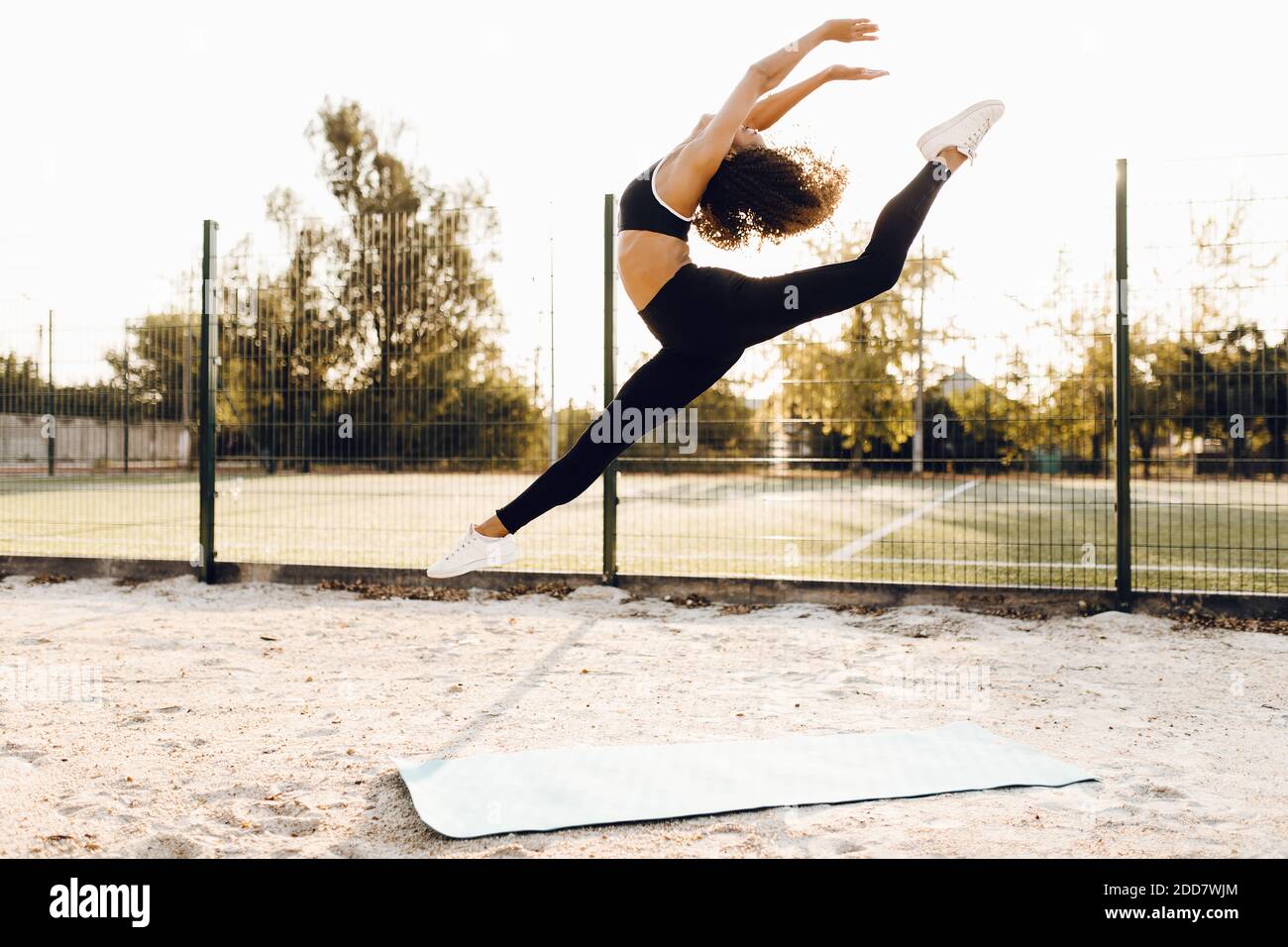 Young athletic african american woman in sportswear long jump at ...