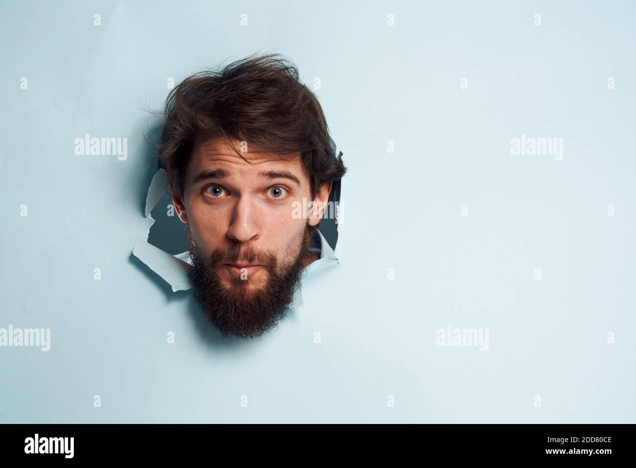 Emotional man peeps his head out of the blue background wall Stock ...