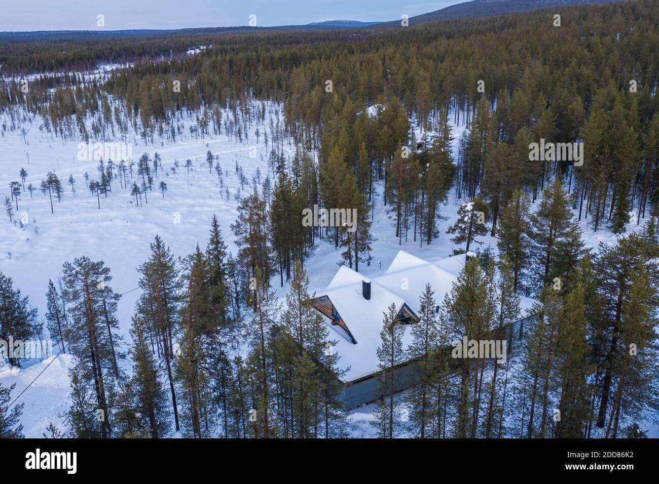Aerial of wooden cabin in the remote forest, with snow covered woods ...