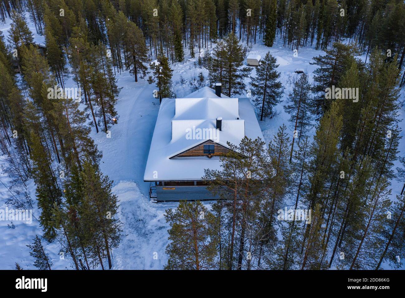 Aerial of wooden cabin in the remote forest, with snow covered woods ...