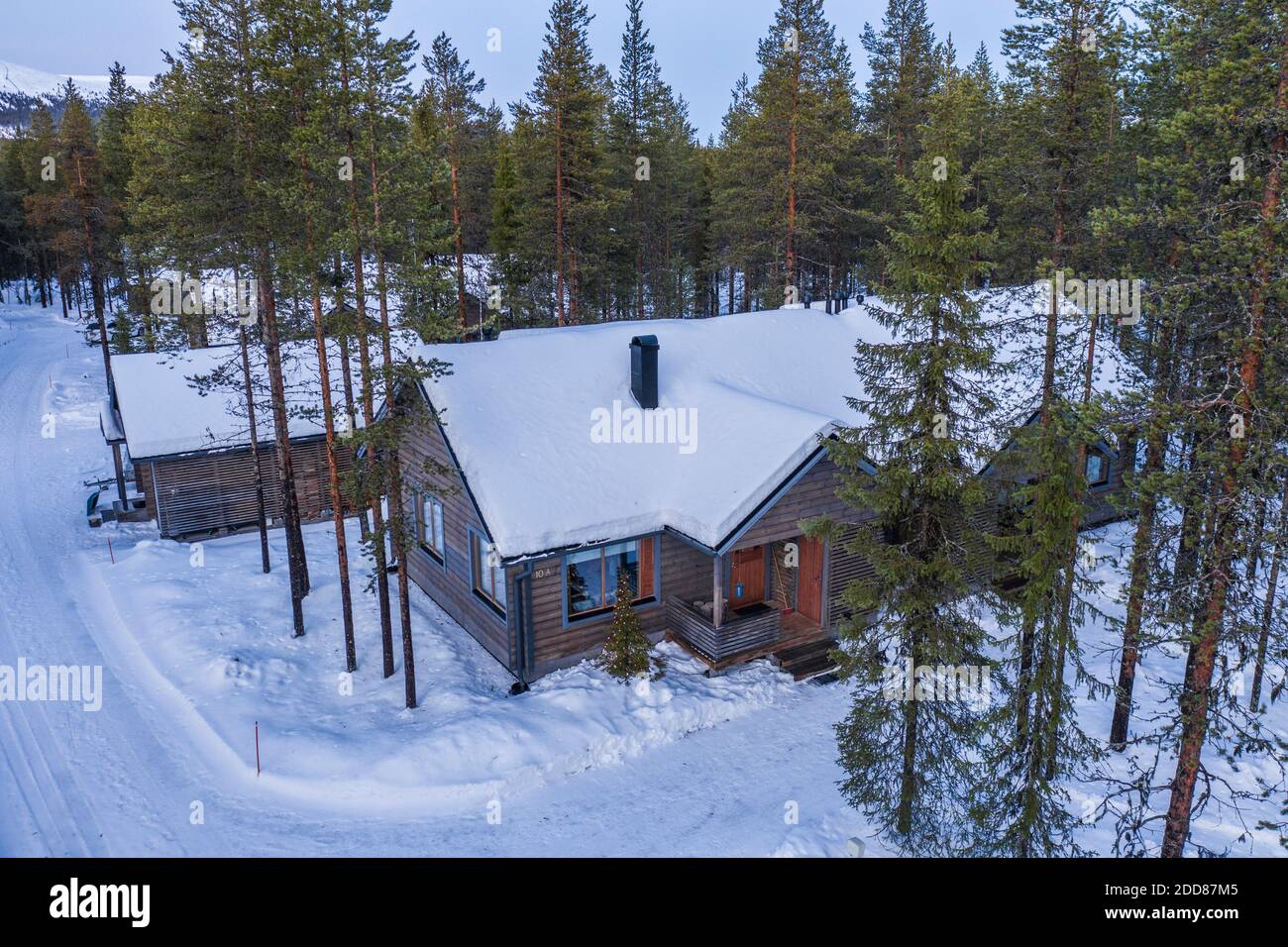Aerial of wooden cabin in the remote forest, with snow covered woods ...