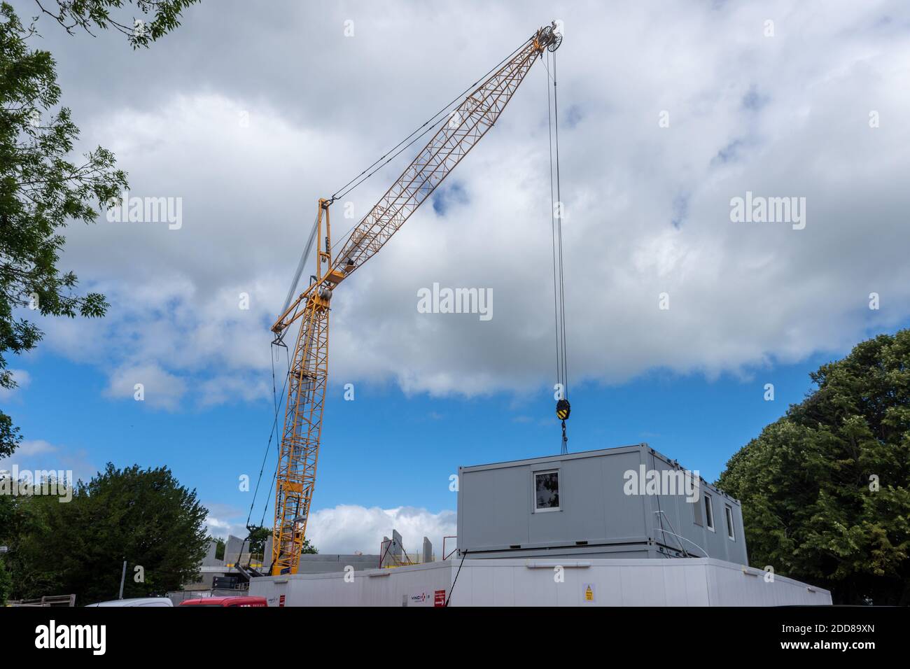 A crane on a building site seen lifting items from behind the temporary ...
