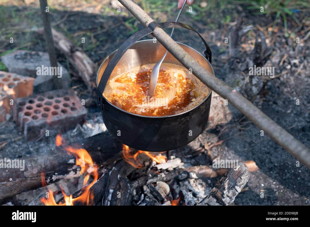 Stir the dish over the fire. Stir the soup with a spoon. The kitchen is ...
