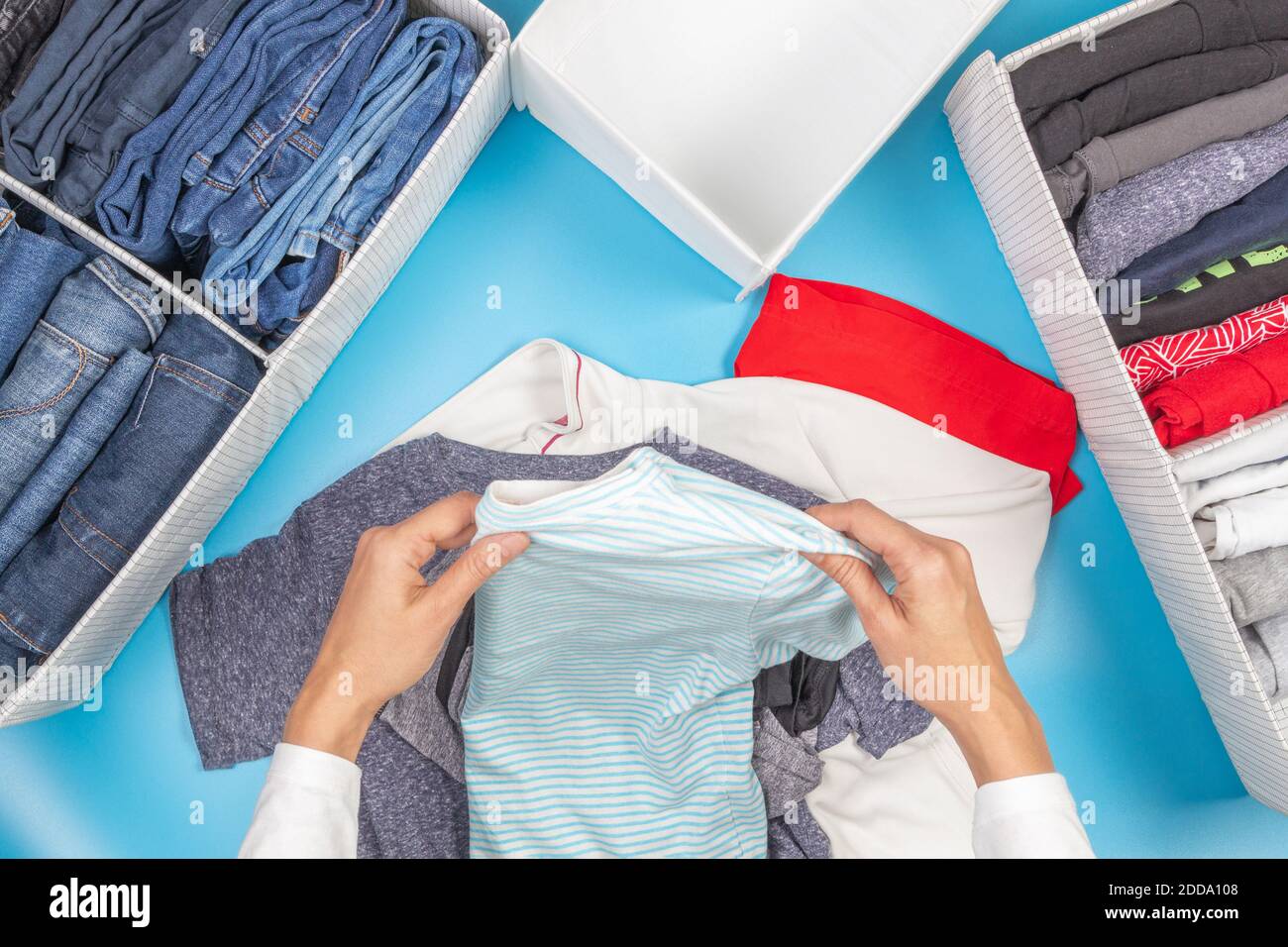 Woman hands folds and puts clothes to baskets. Vertical storage of ...