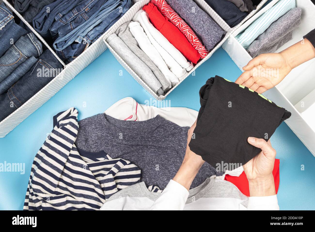 Woman and kid hands folds and puts clothes to baskets. Vertical storage ...