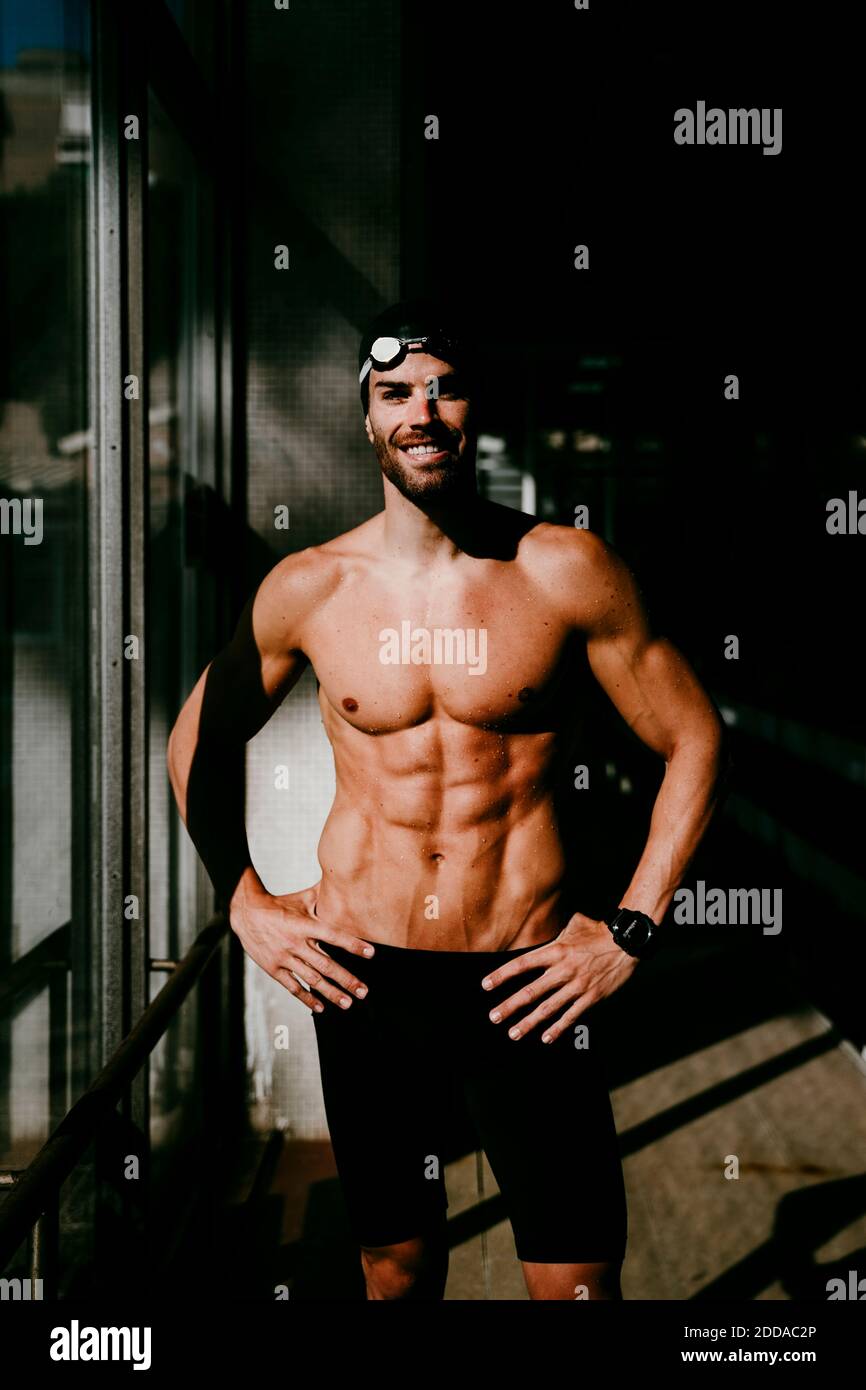 Smiling male swimmer standing by window in locker room Stock Photo - Alamy