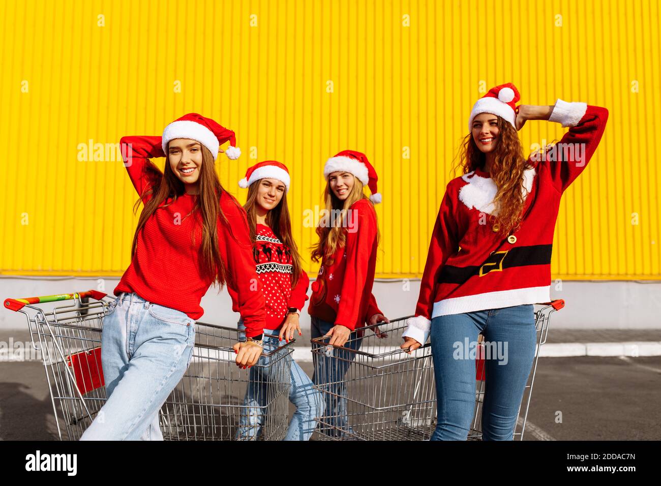Group of four young women in Christmas sweaters and Santa Claus hats ...