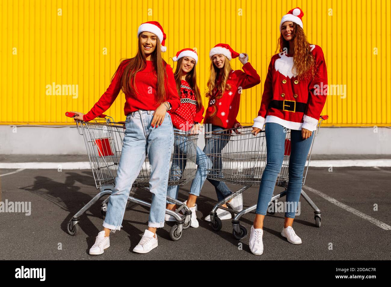 Group of four young women in Christmas sweaters and Santa Claus hats ...