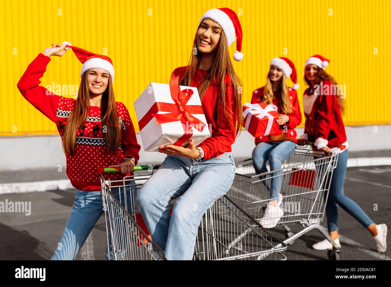 Group of four young women in christmas sweaters and santa claus hats ...