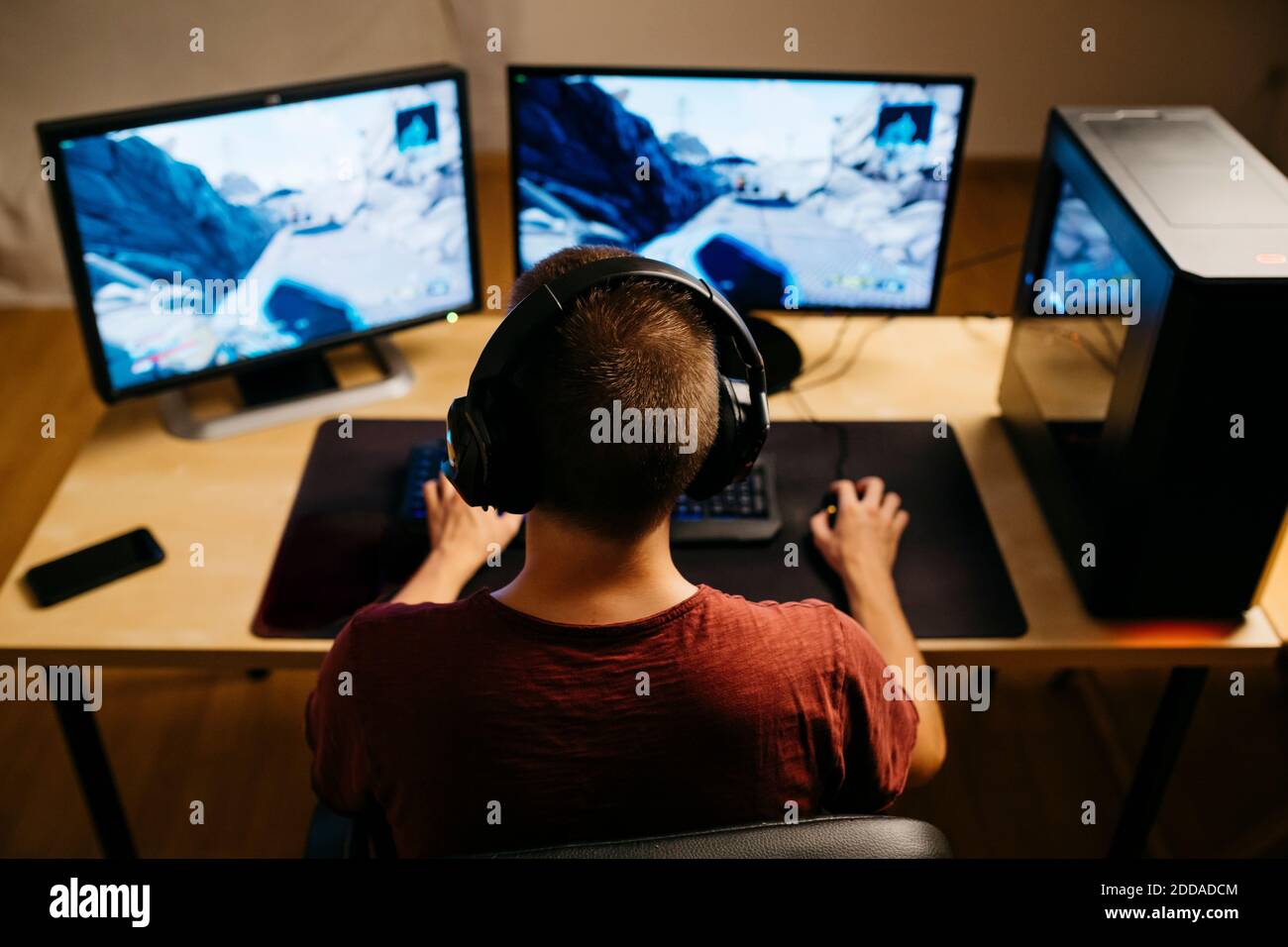 Young man playing video games with computer at desk Stock Photo - Alamy