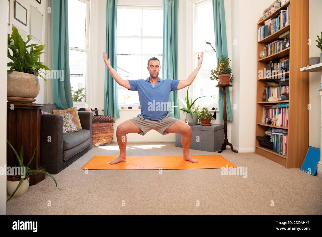Mature man doing crouching exercise at home Stock Photo - Alamy