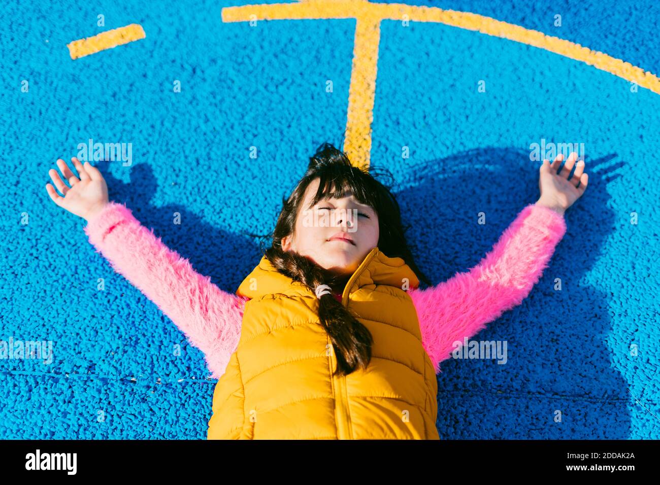 Girl relaxing with arms raised on basketball court Stock Photo - Alamy