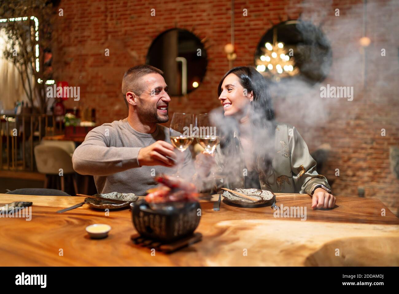 Smiling friends toasting drink while sitting by table at restaurant ...